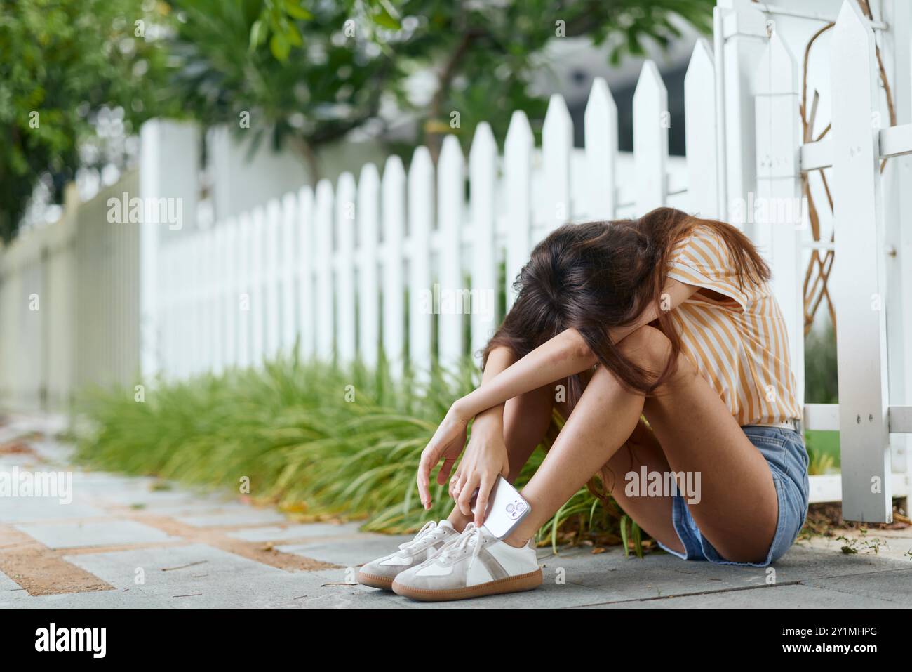 sad young woman sitting on the ground, feeling distressed, casual ...