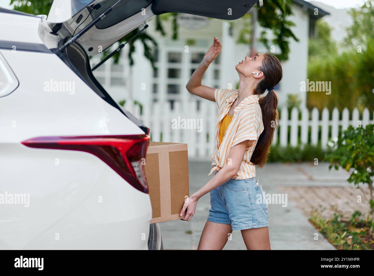 woman unloading box from car, sunny outdoor setting, focus on daily ...