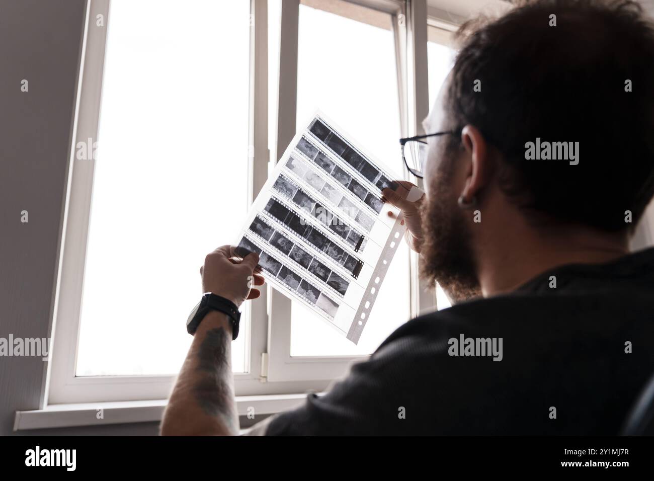 Photographer examining film negatives by the window Stock Photo - Alamy