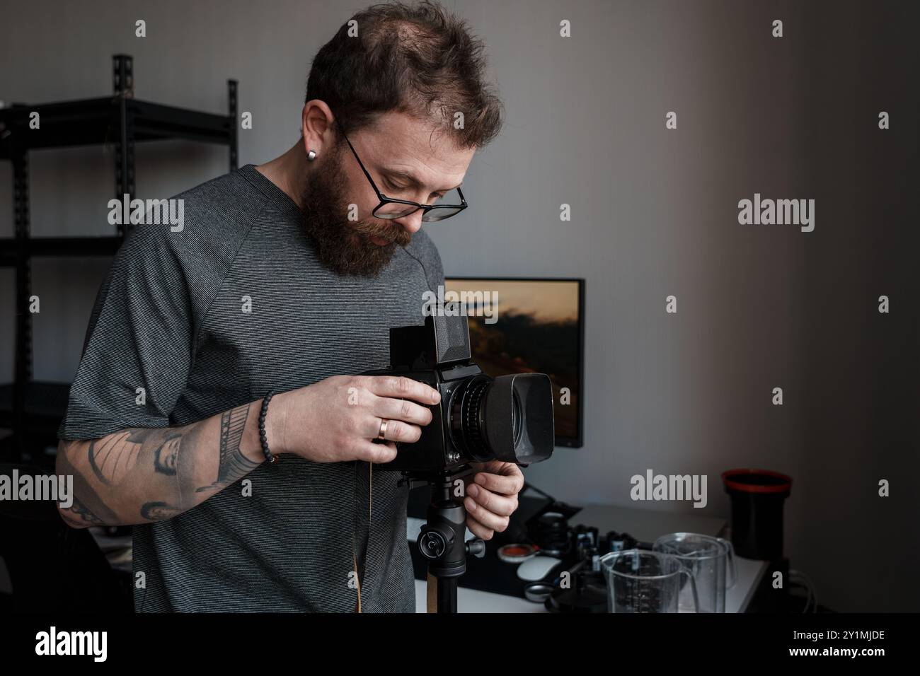 Male photographer adjusting camera on tripod indoors Stock Photo - Alamy