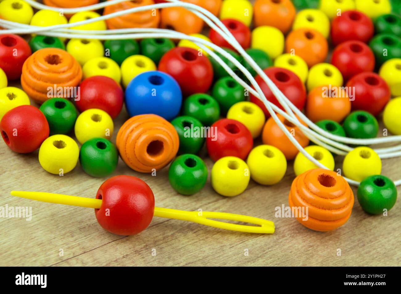 Colorful wooden craft beads and needle Stock Photo - Alamy