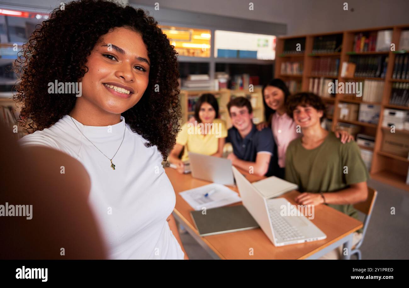 Cheerful selfie of a group of friends in a library gathered to study ...