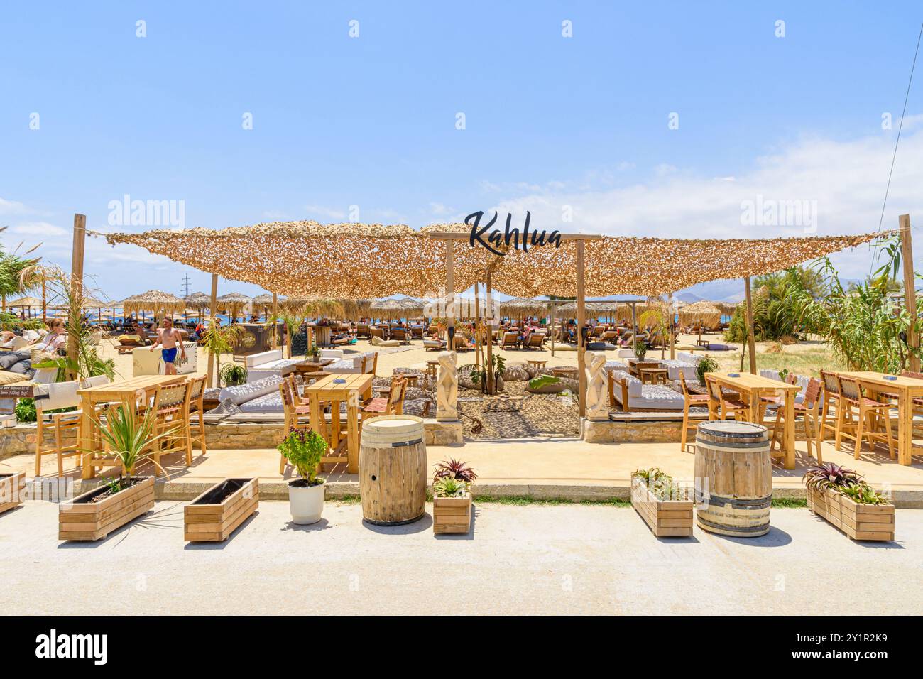 Tables and chairs behind sun loungers at a beach bar on Agios Prokopios ...