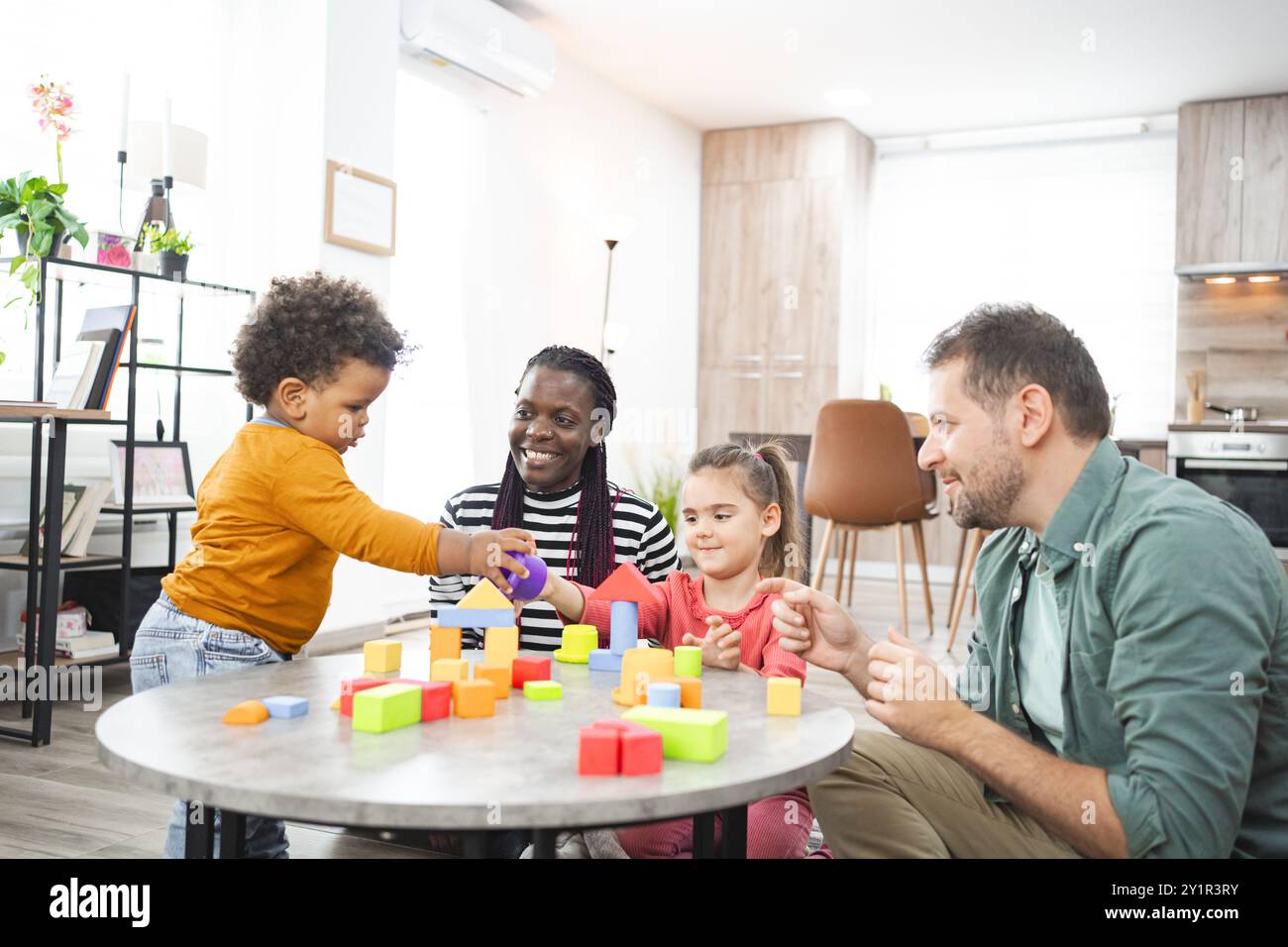 Multiracial family playing with colorful blocks in bright living room ...
