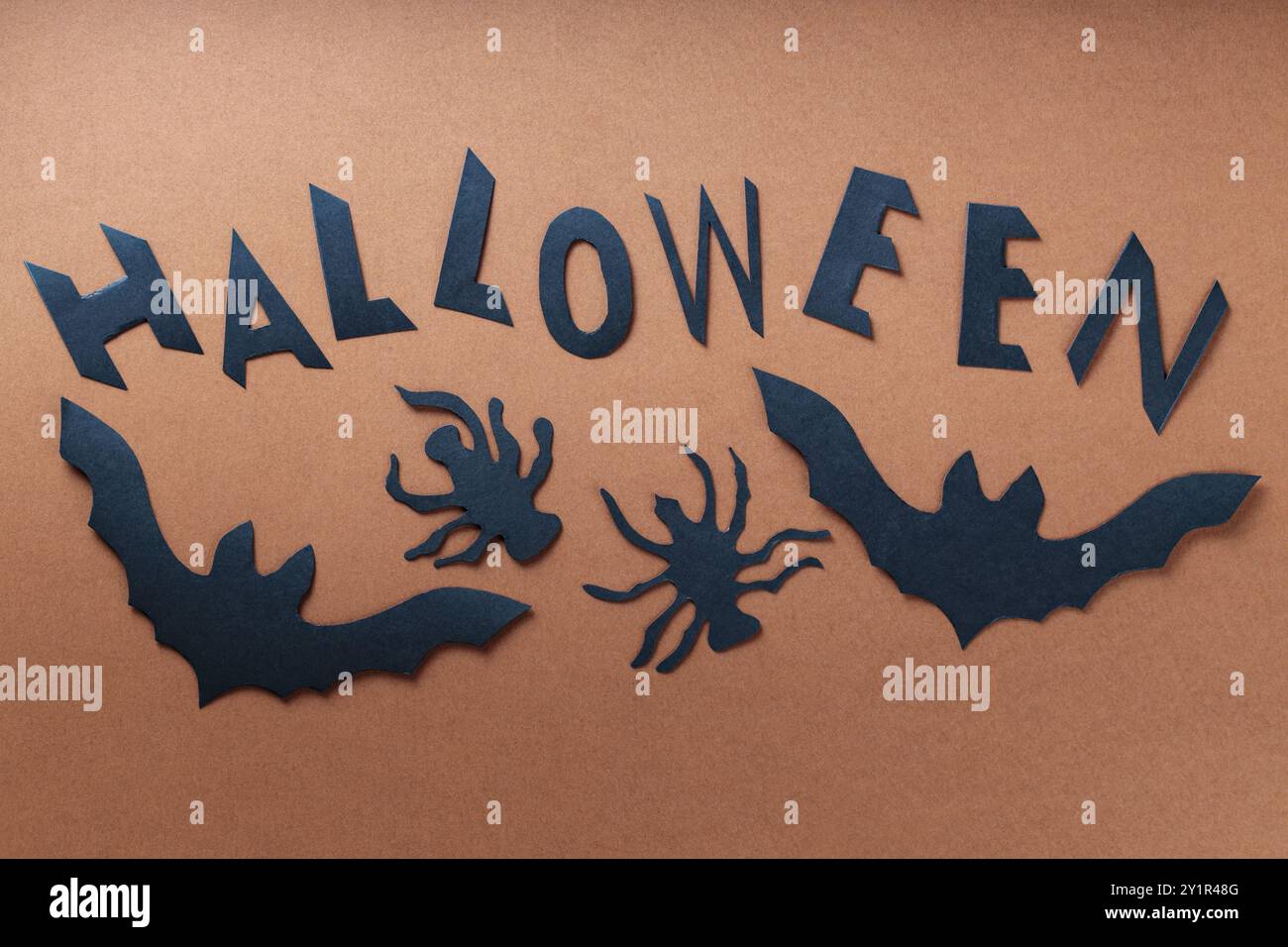 Black Paper Cutouts of Bats, Spiders and Word Halloween on Brown ...