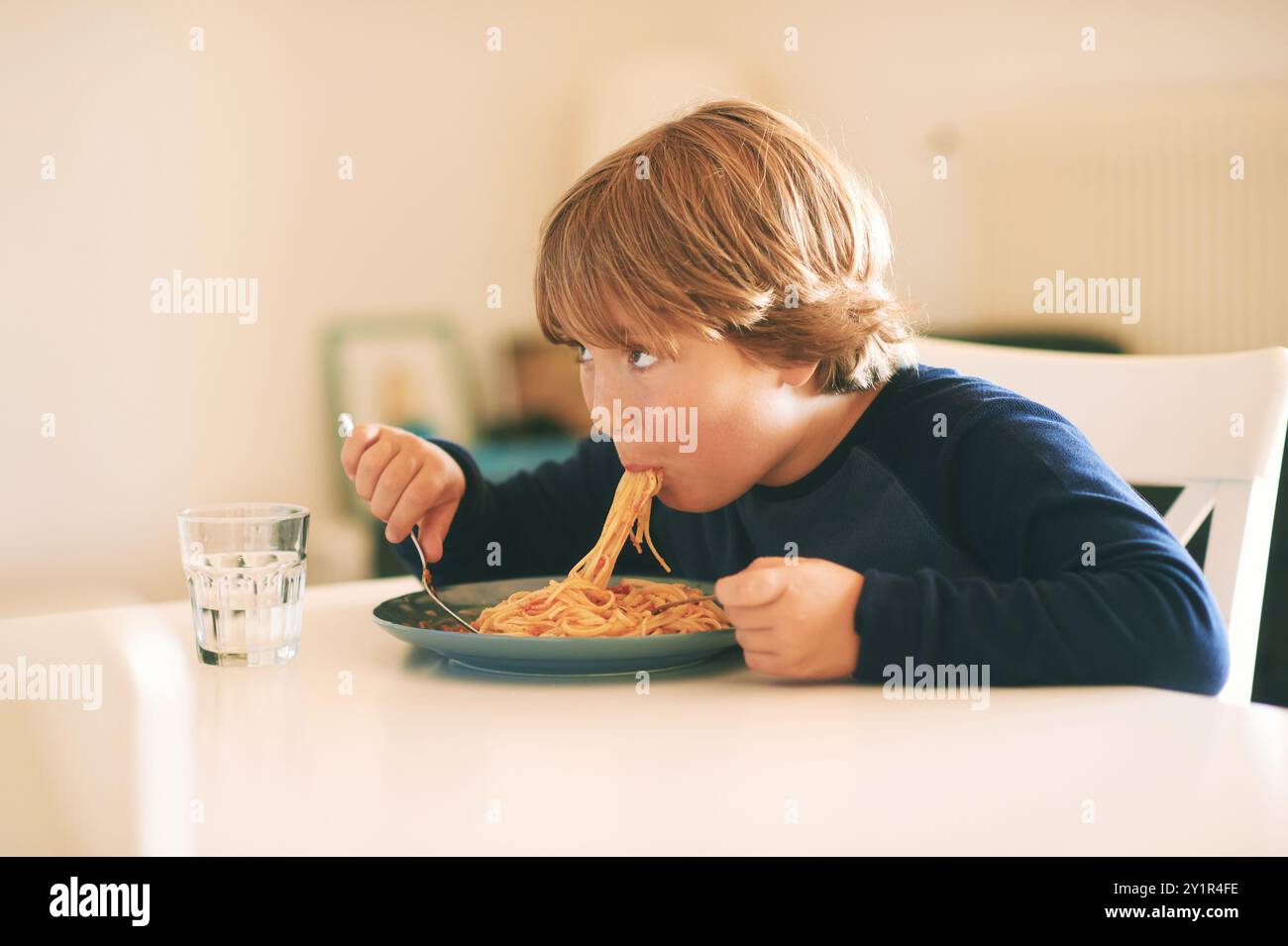 Home portrait of cute little boy eating pasta with tomato sauce Stock ...