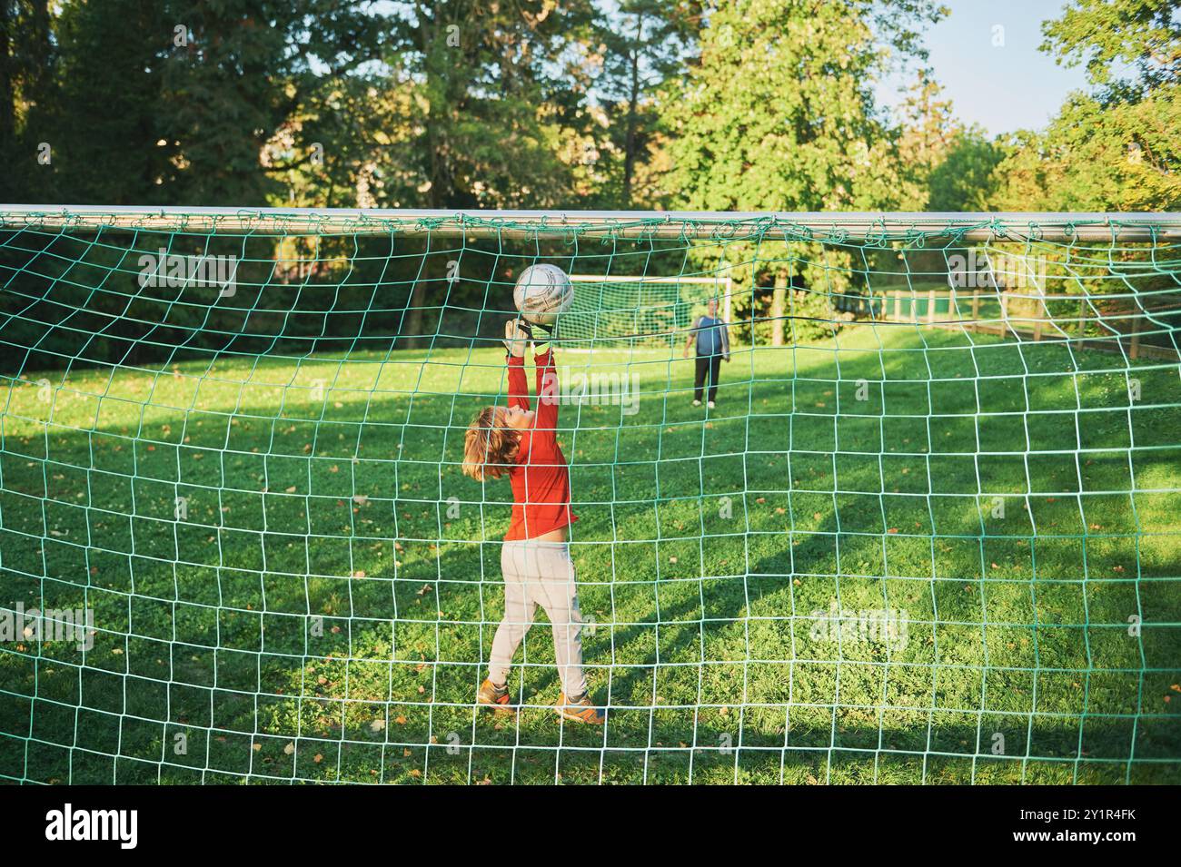 Little boy playing football with his father, kid goalkeeper defending ...