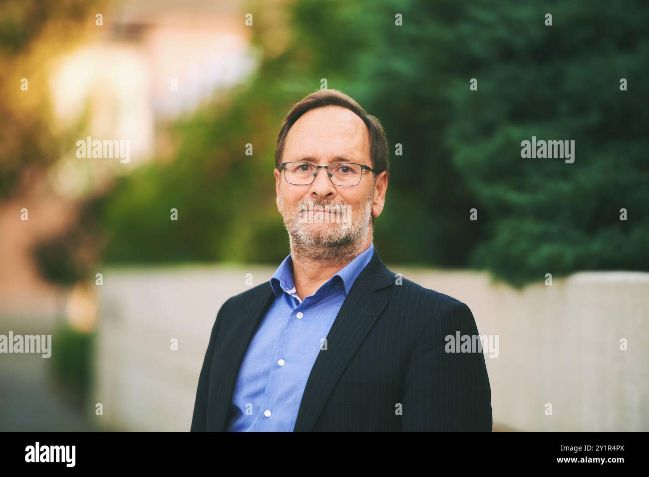 Outdoor portrait of handsome middle age man wearing suit, posing in ...