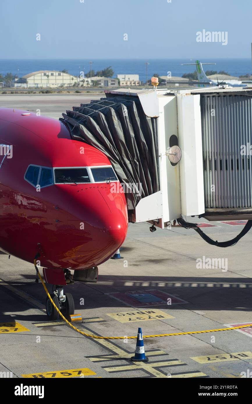 Red airplane at an airport with an access bridge to the aircraft ...