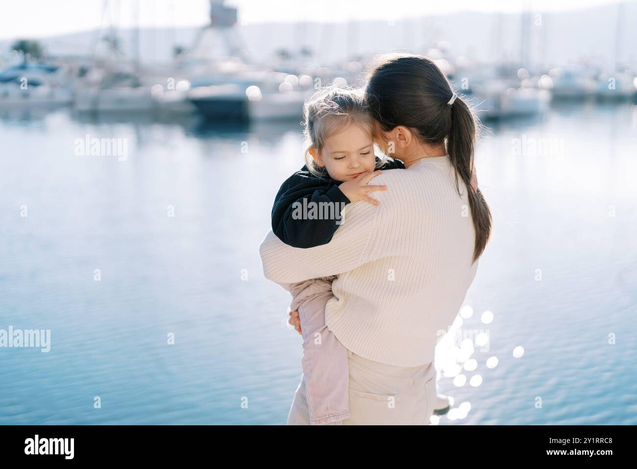 Mother hugs the little girl in her arms, touching their foreheads with ...