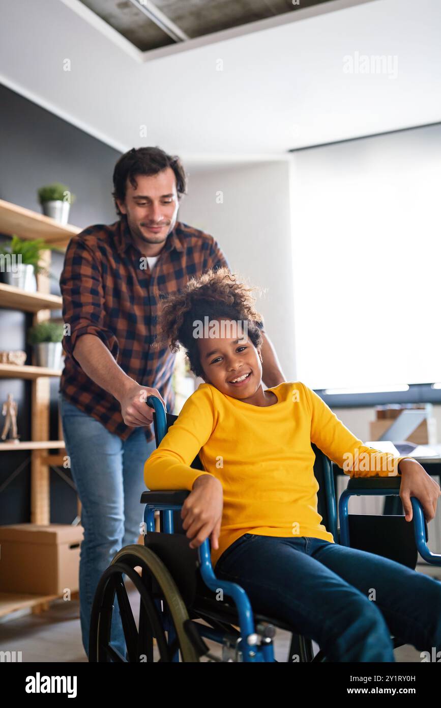 Child with disability in wheelchair at home having fun with father ...