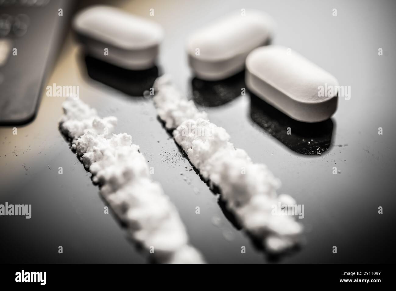 Close-up of white pills and lines of powdered substance, illustrating ...