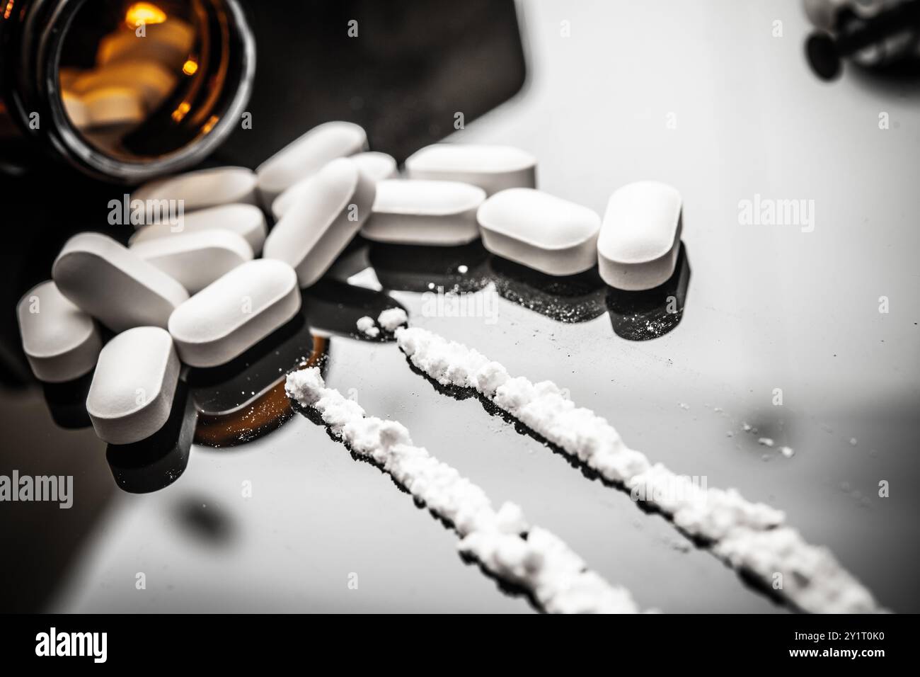 Prescription opioids and raw fentanyl powder scattered on a reflective ...