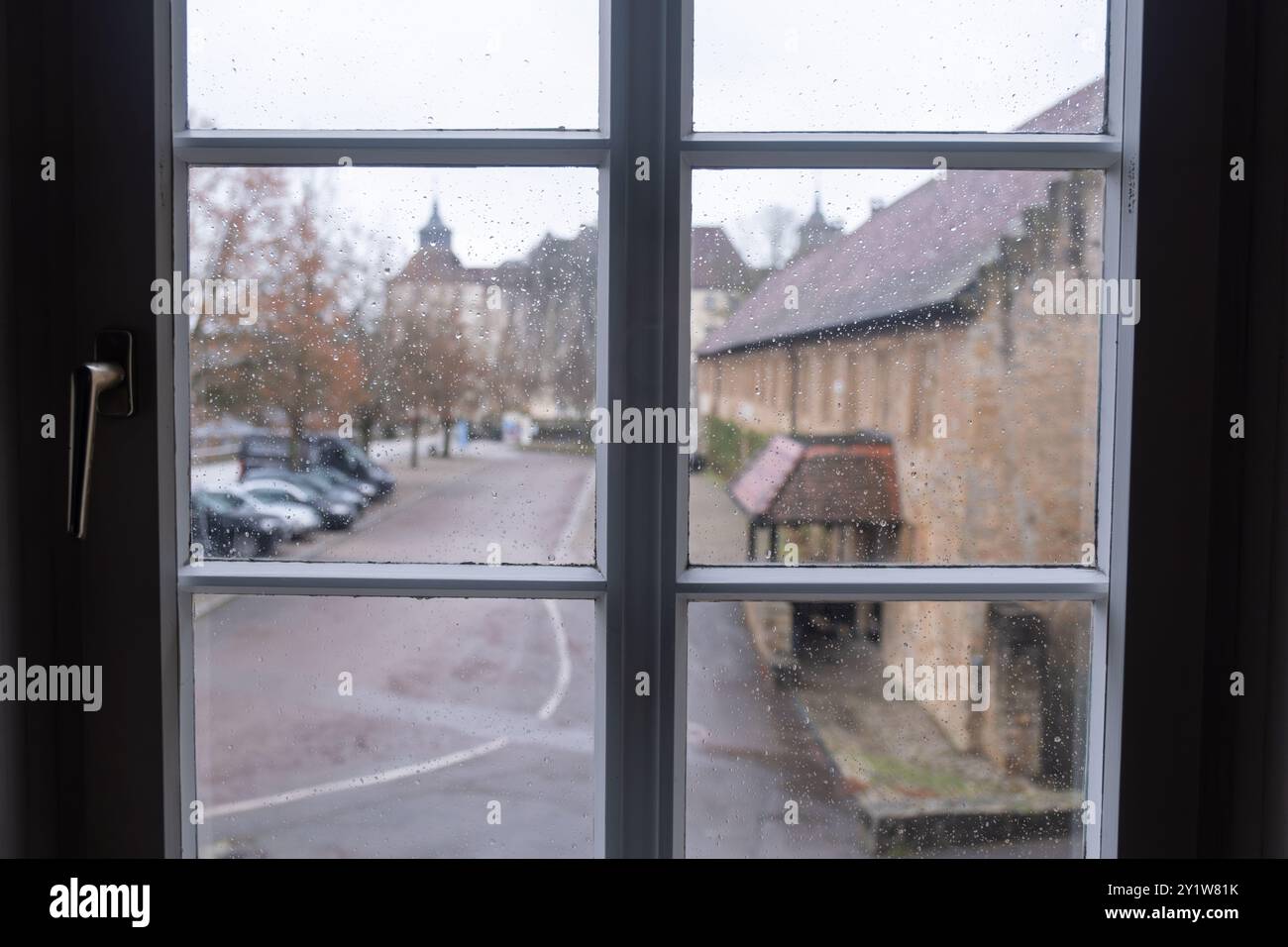 A rainy day view through a window, with droplets on the glass, showing ...