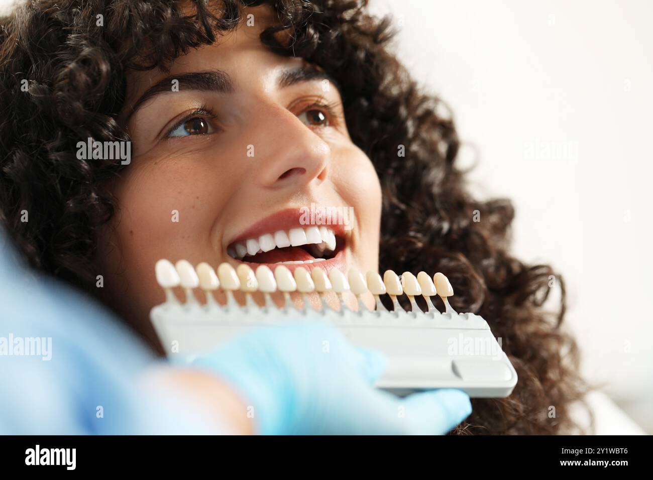 Doctor checking young woman's teeth color in clinic, closeup. Dental ...