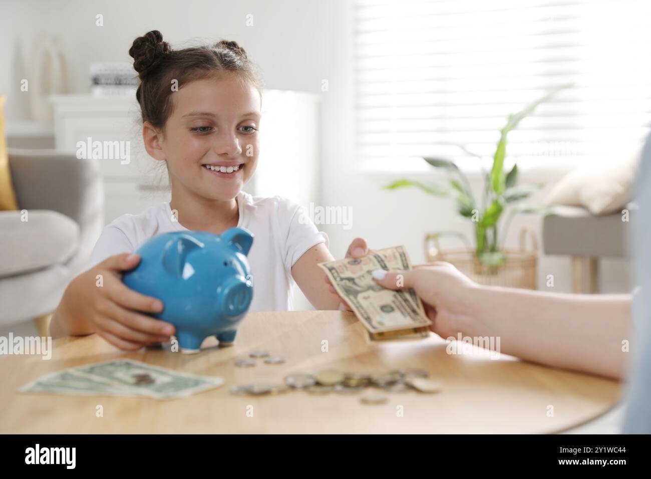 Mother giving pocket money to her daughter at table indoors Stock Photo ...