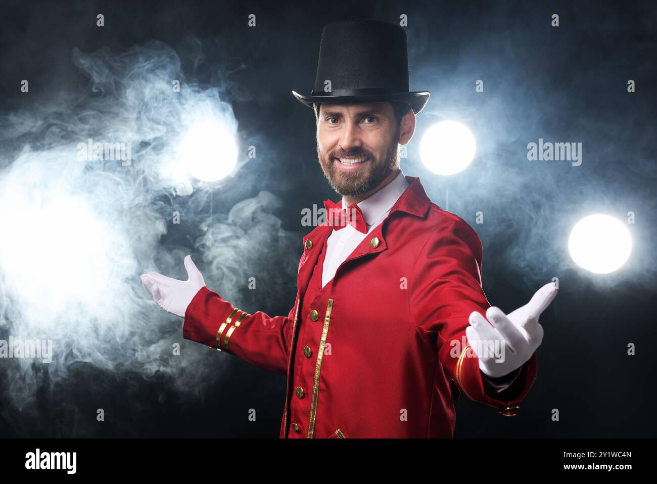 Portrait of showman in red costume and hat on black background with ...