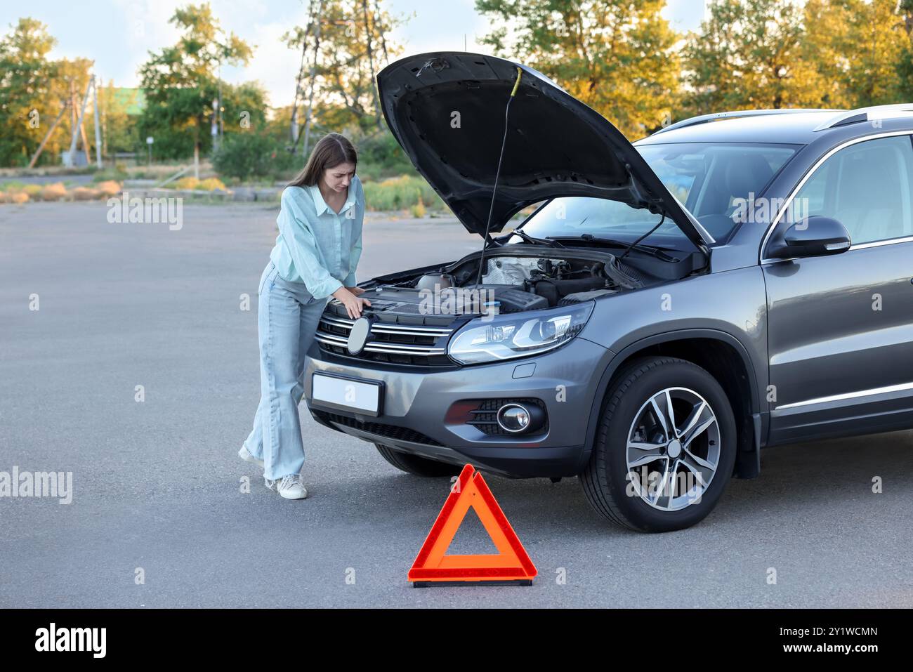Stressed woman looking under hood of broken car outdoors Stock Photo - Alamy