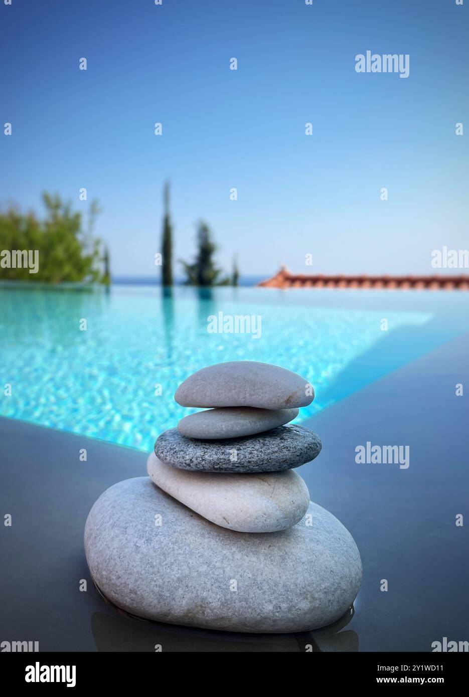 pile of balancing stones at the edge of an outdoor swimming pool in ...