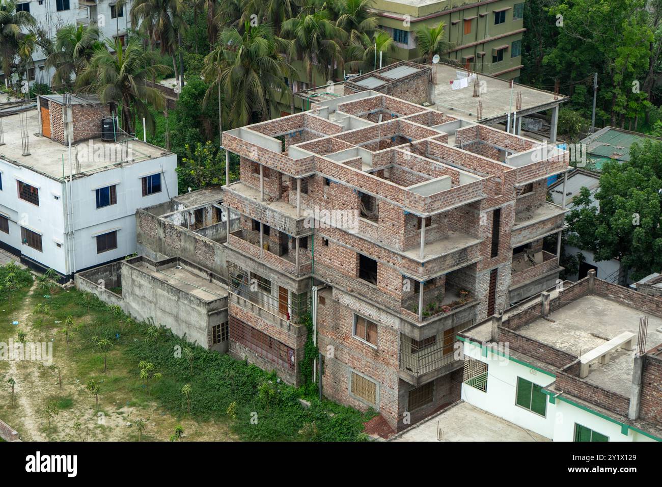 under-construction brick building amidst residential area with greenery ...