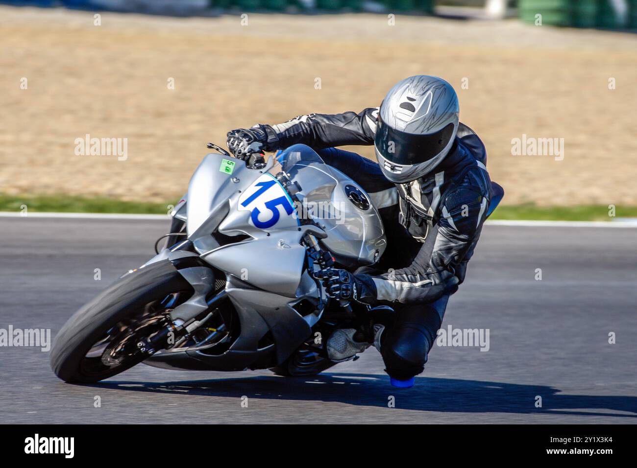 A motorcycle racer in full gear leans into a high speed turn on a ...