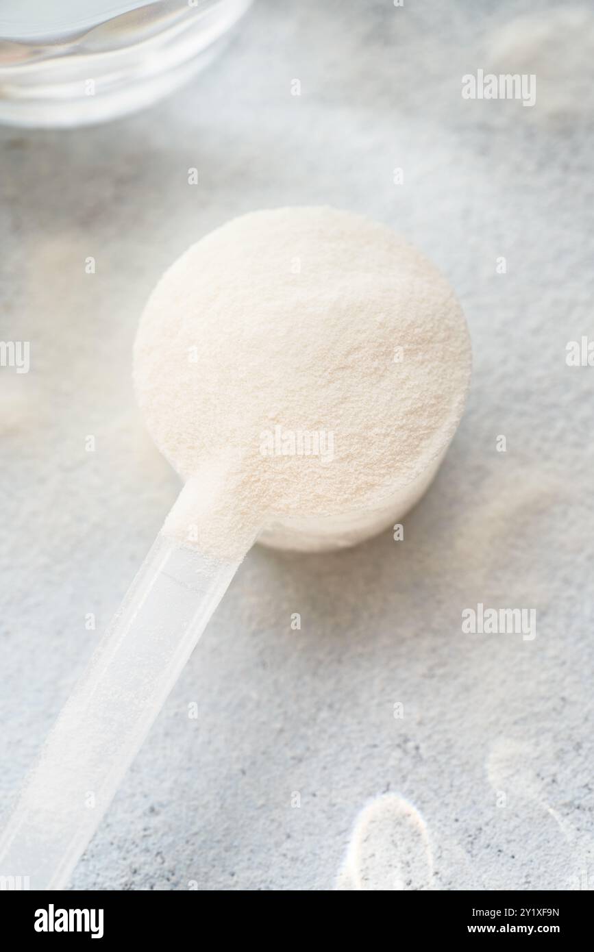 Collagen powder in a plastic measuring spoon and a glass of water Stock ...