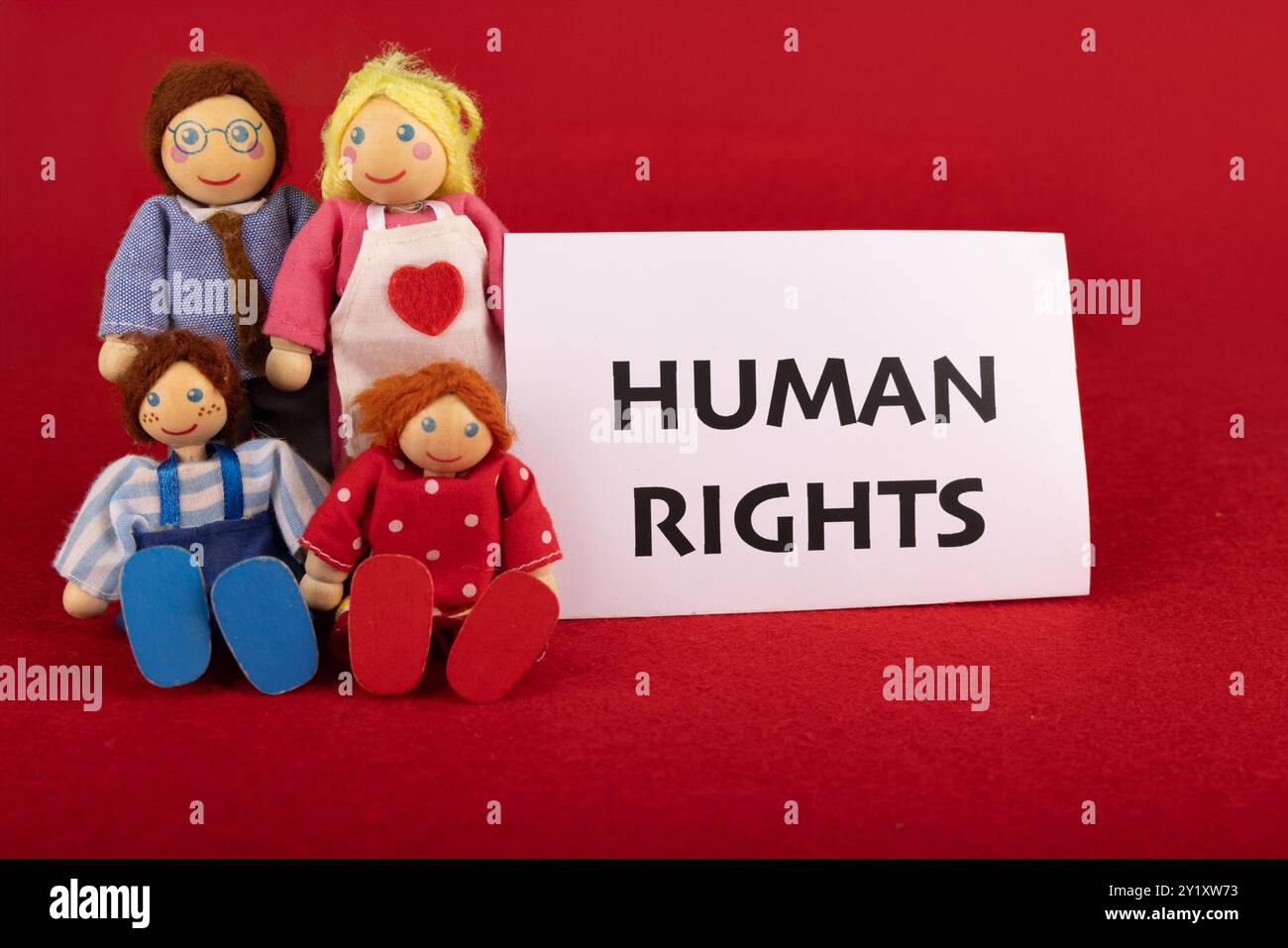 Wooden figures alongside a "Human Rights" board, captured on a red and ...
