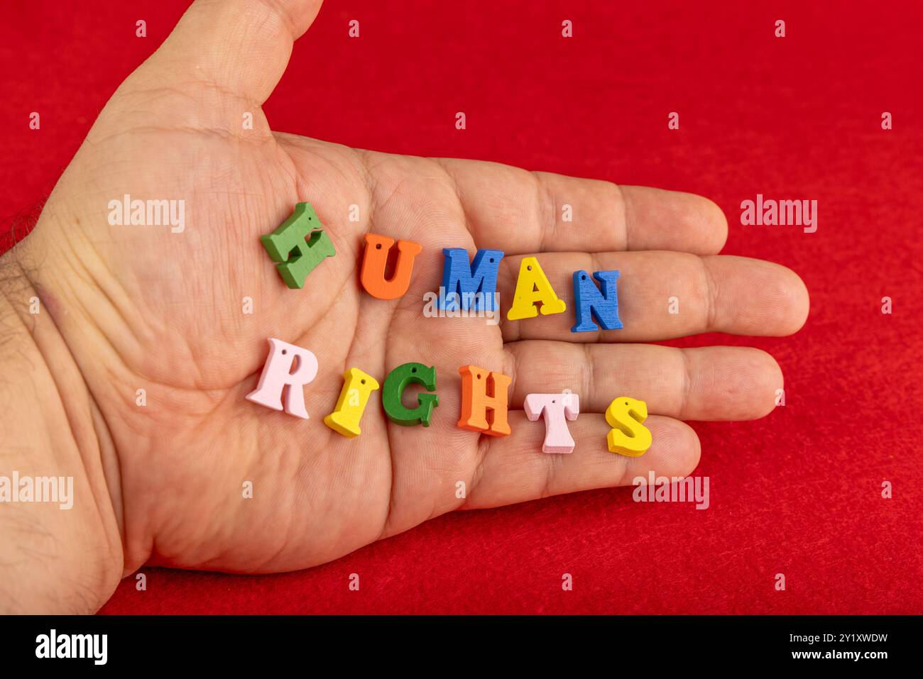 A close-up of a hand holding vibrant wooden letters forming the phrase ...