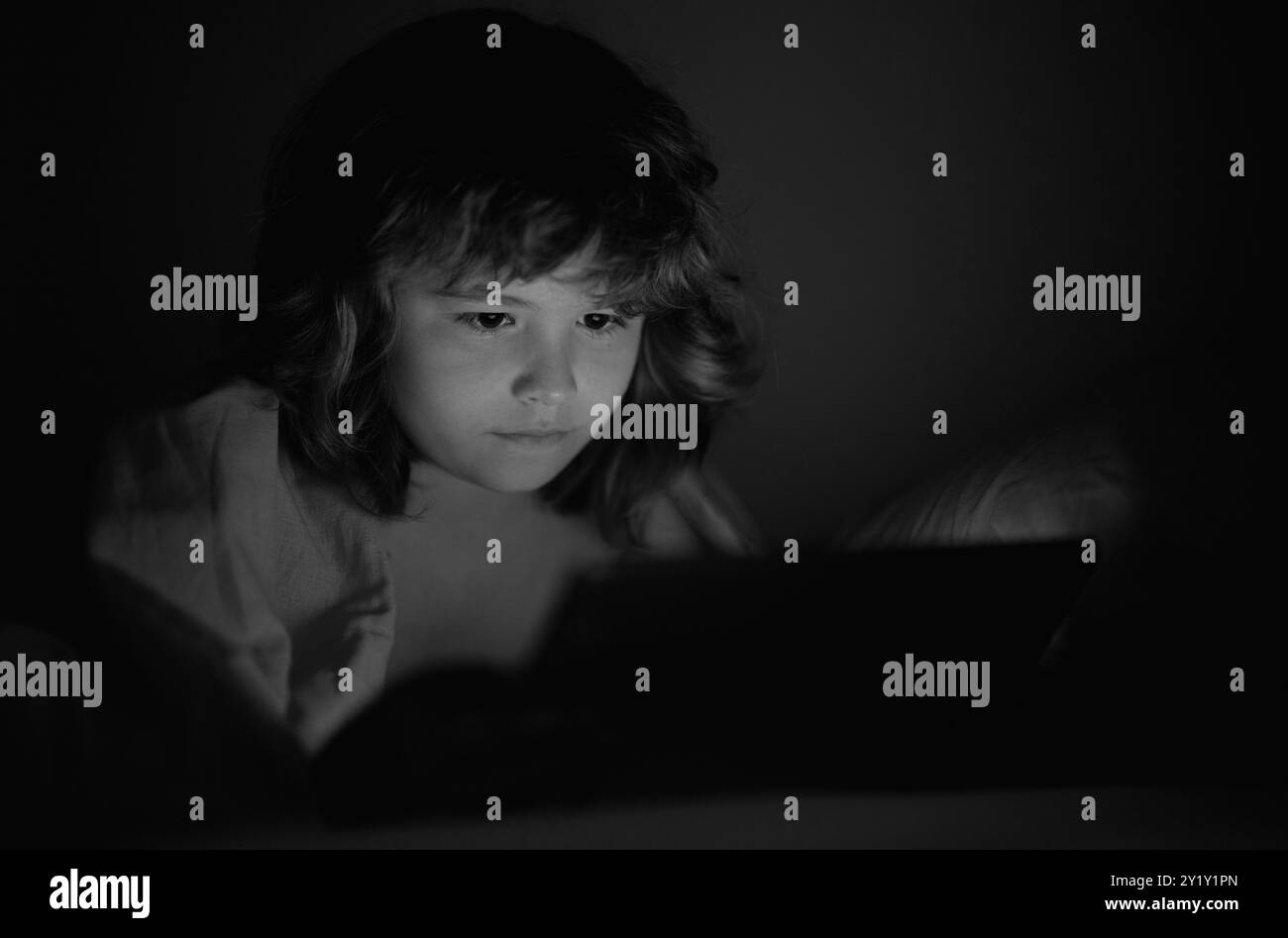 Child gadget addiction and insomnia. The childs face is illuminated by ...