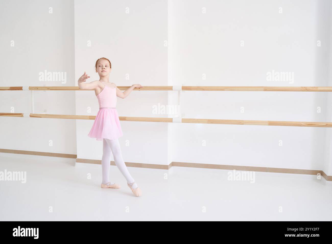 Young ballet girl at studio lesson. Training performance. Stretching ...