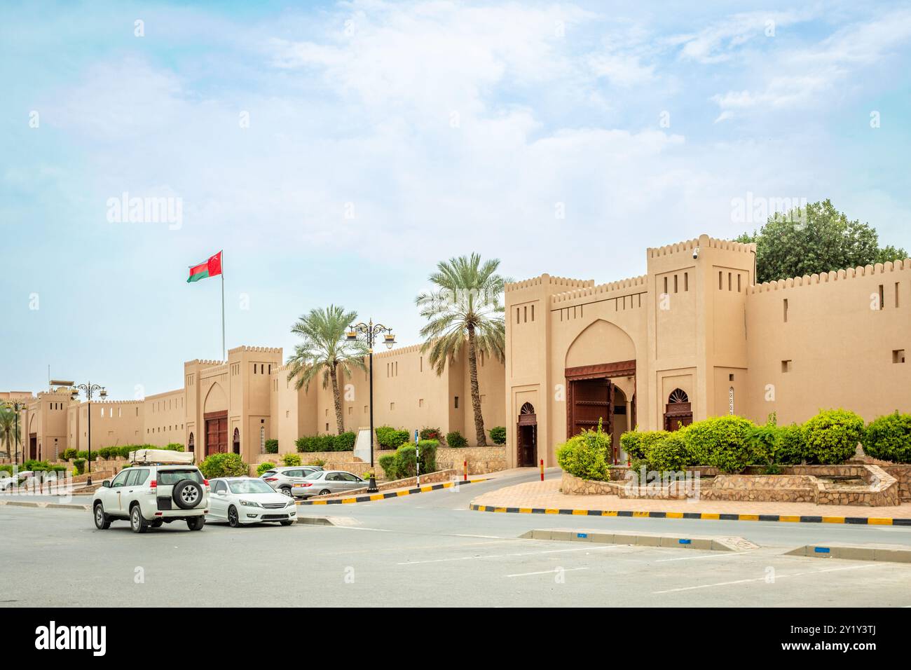 Fortified walls and gate to the arab souq market with omani flag waving ...