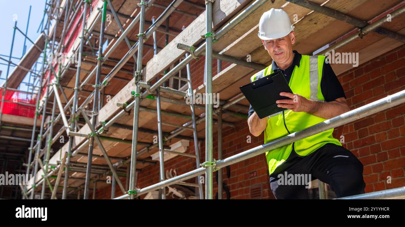 Male builder foreman, construction worker or site manager writing on a ...