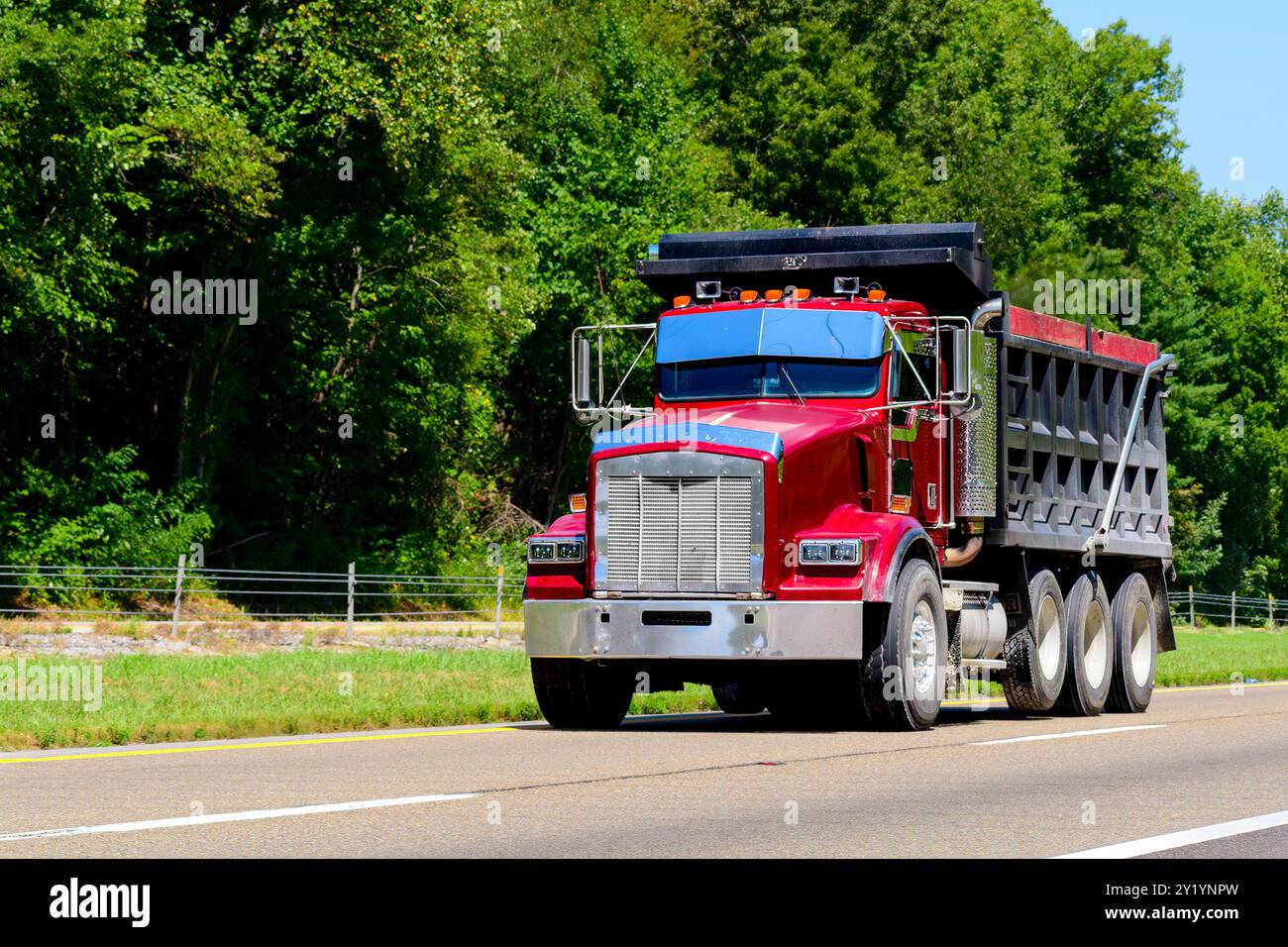 Horizontal shot of a heavy duty red dump truck going down the highway ...