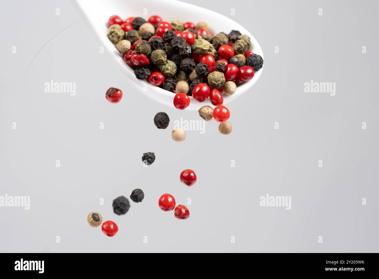 Different types of peppercorns pouring. Red, green, white and black ...