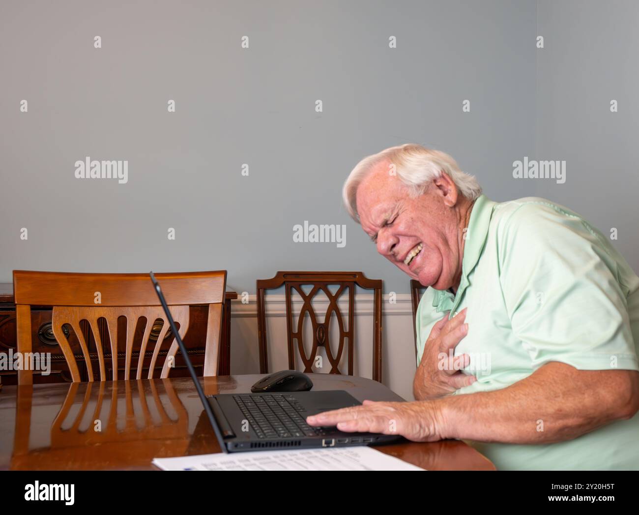 Older man with white hair wearing a green shirt is working on his ...