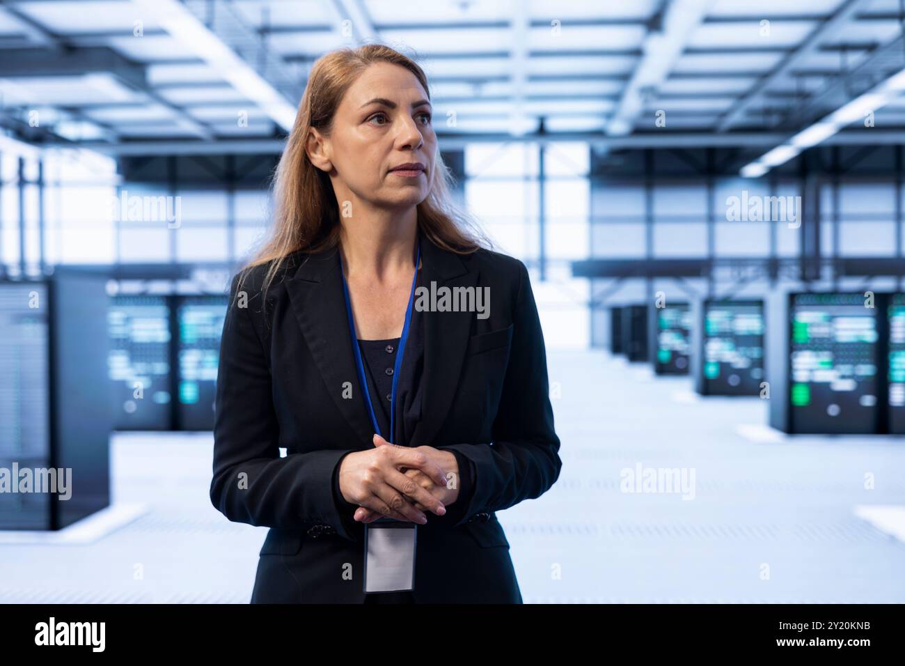 IT staff member walking between server rows in data center, doing yearly infrastructure ...