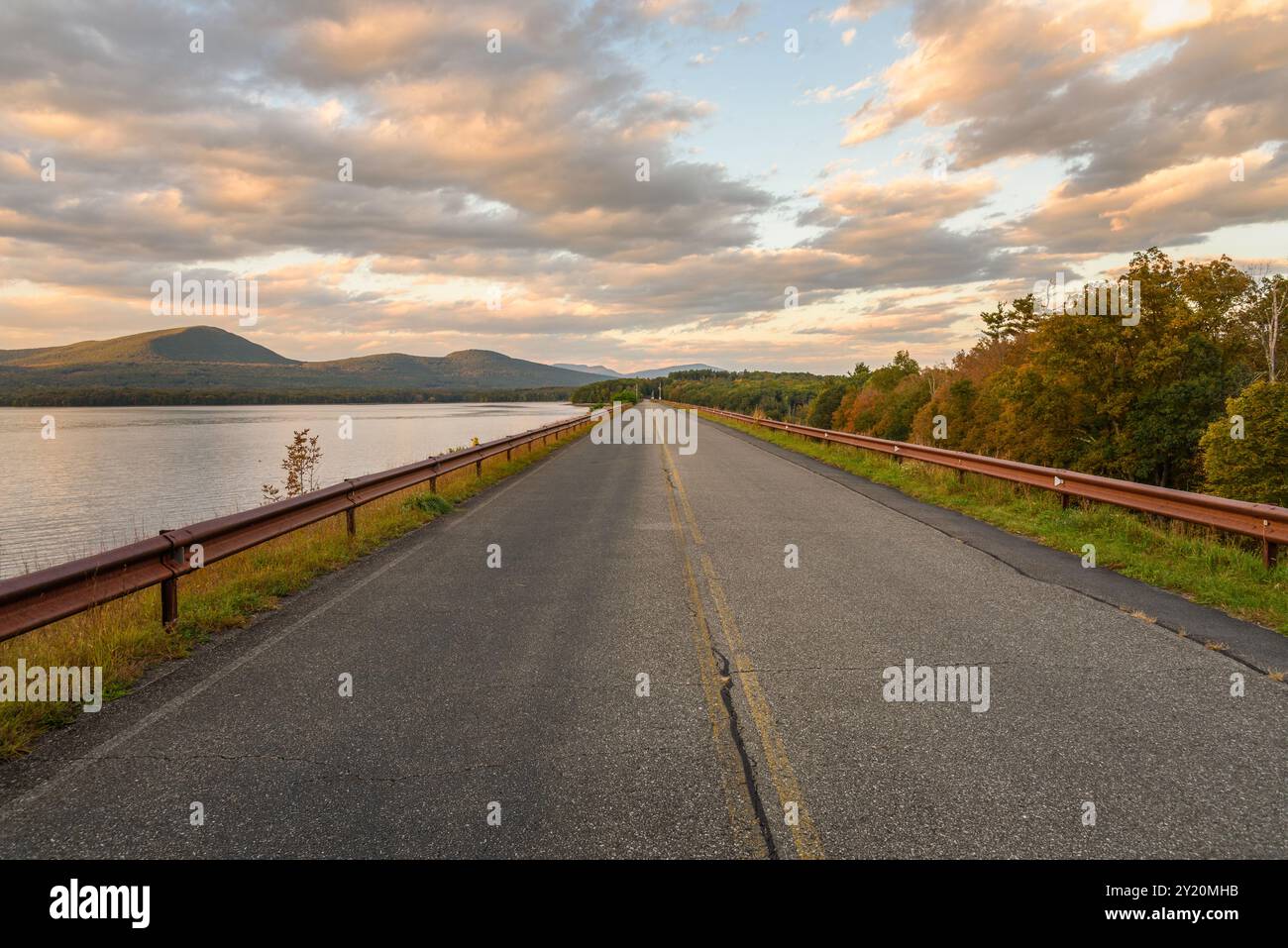 Empty road running over a dam in a forested mountain landscape under ...