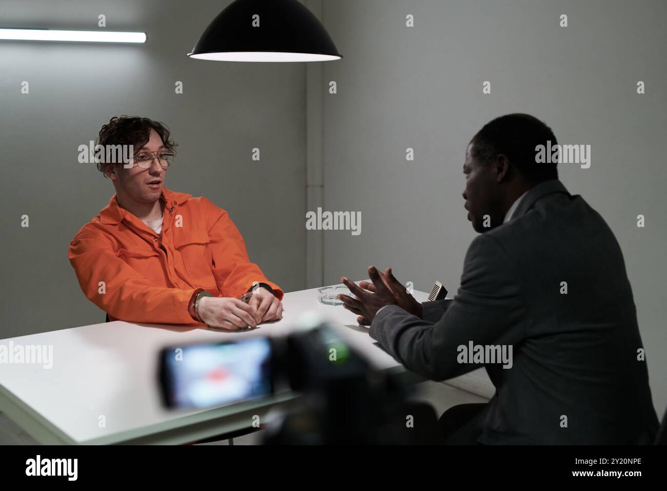 Lawyer engaging client in orange jumpsuit during intense interrogation ...