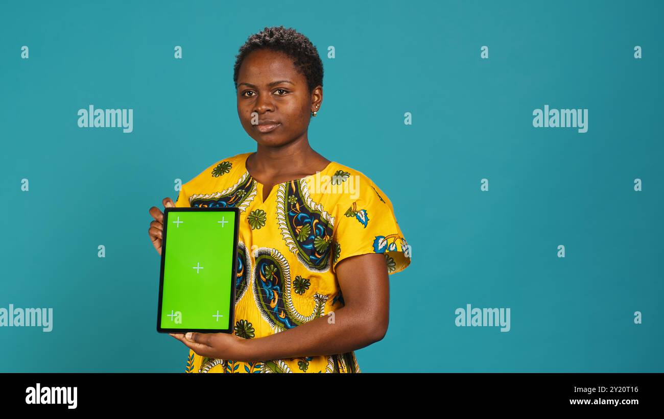 Gorgeous model presenting a tablet with green screen mockup, holding ...