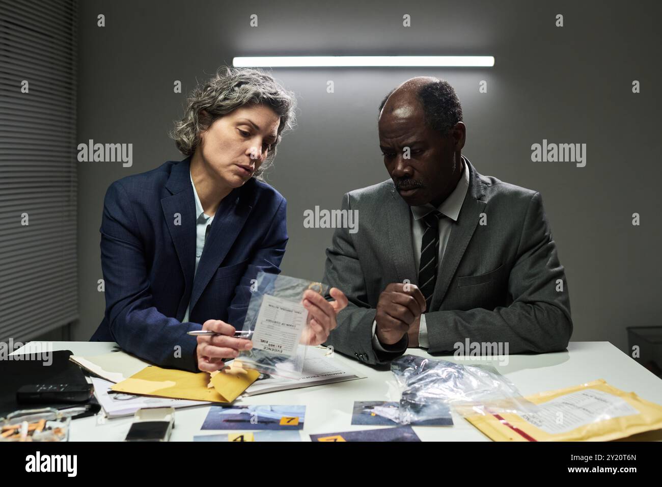 Two detectives examining evidence and discussing crucial aspects of ...