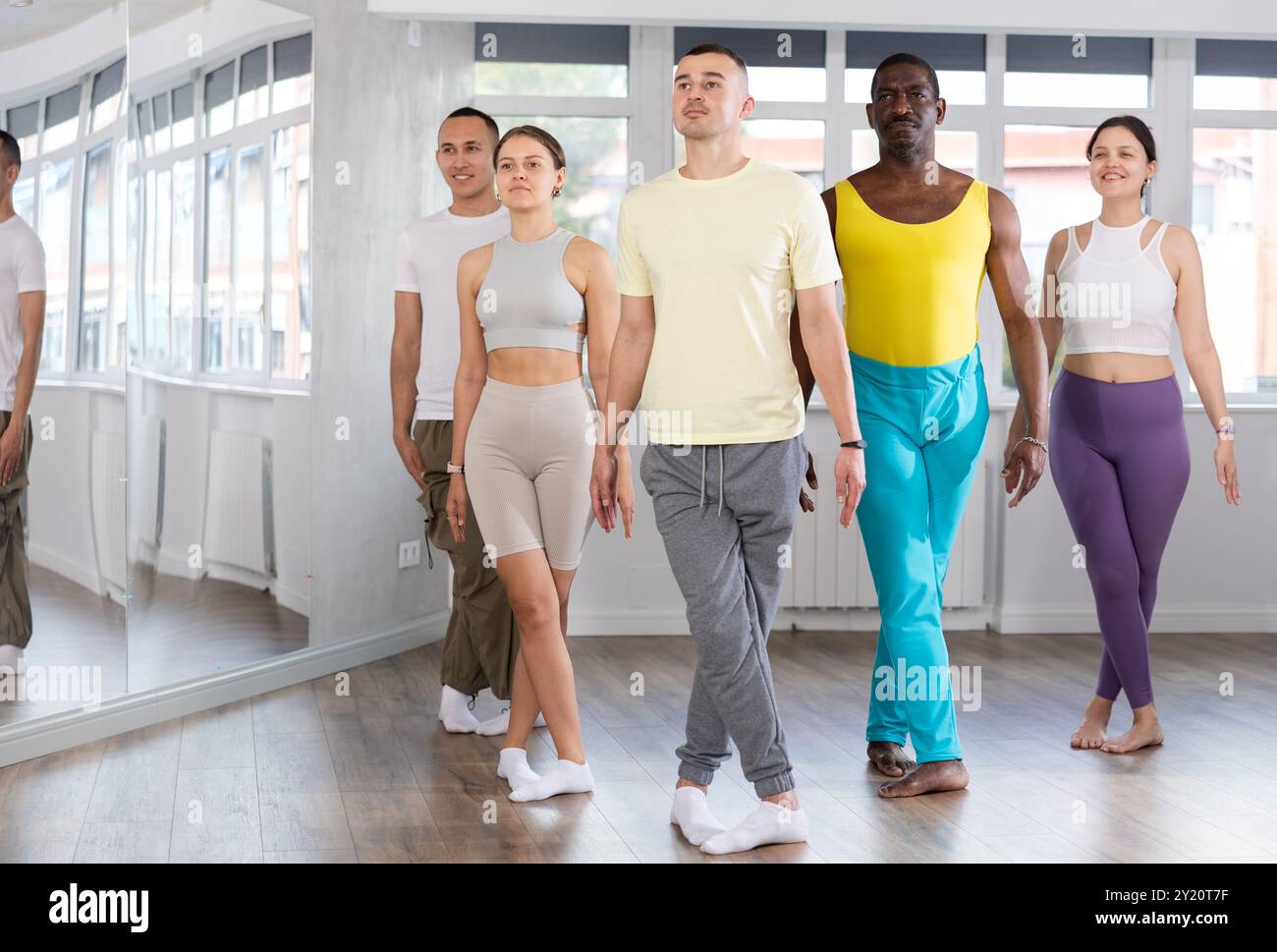 Multinational group of young people stand in row holding hands ...