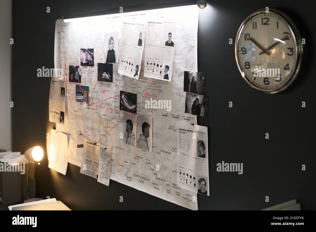 Researcher examining crime scene photos and related documents pinned on ...