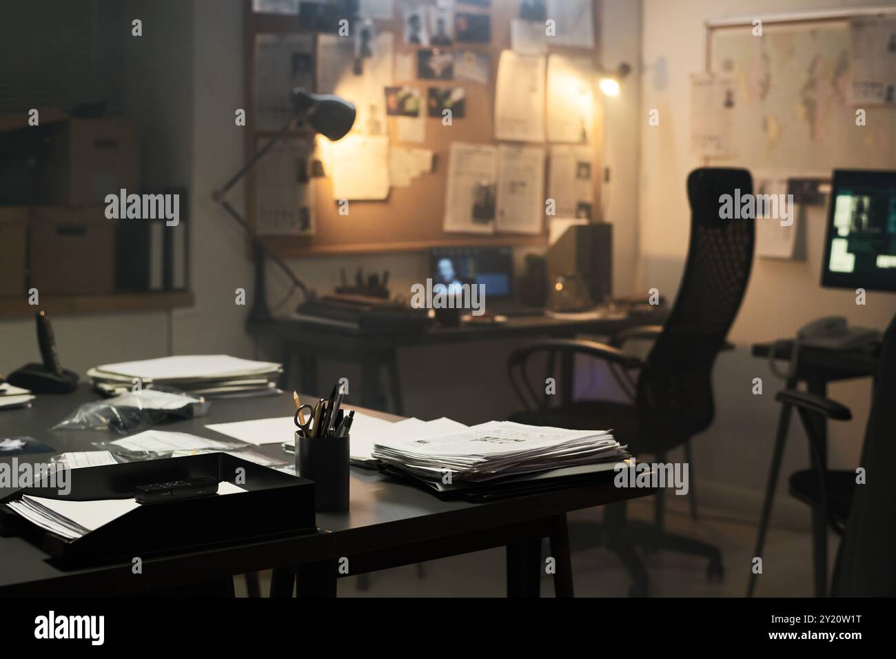 Investigating setting in dimly lit office with papers scattered on desk ...