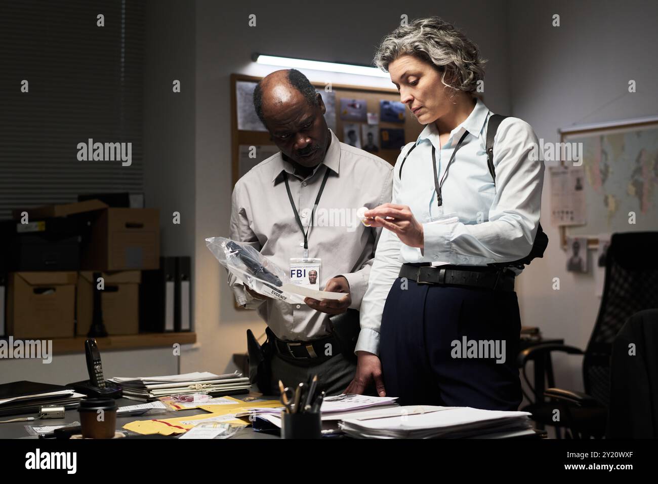 Two people in professional attire are studying evidence in an office ...