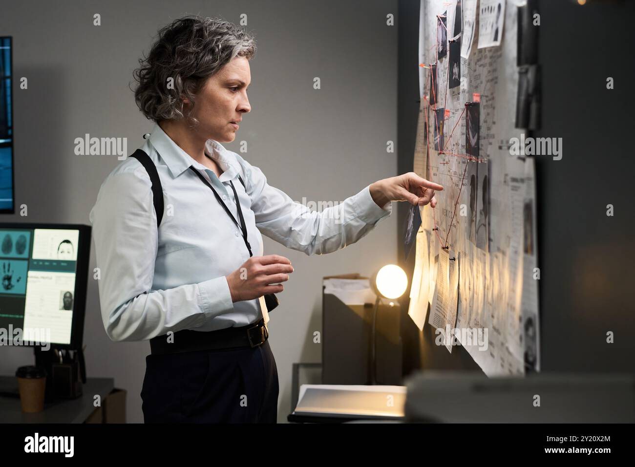 Female detective with short hair analyzing crime scene evidence on ...