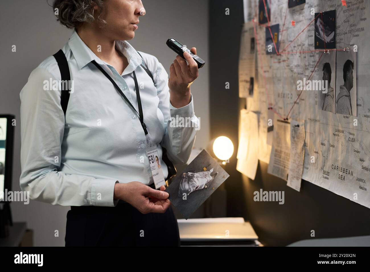 Forensic investigator holding evidence while examining pinned documents ...