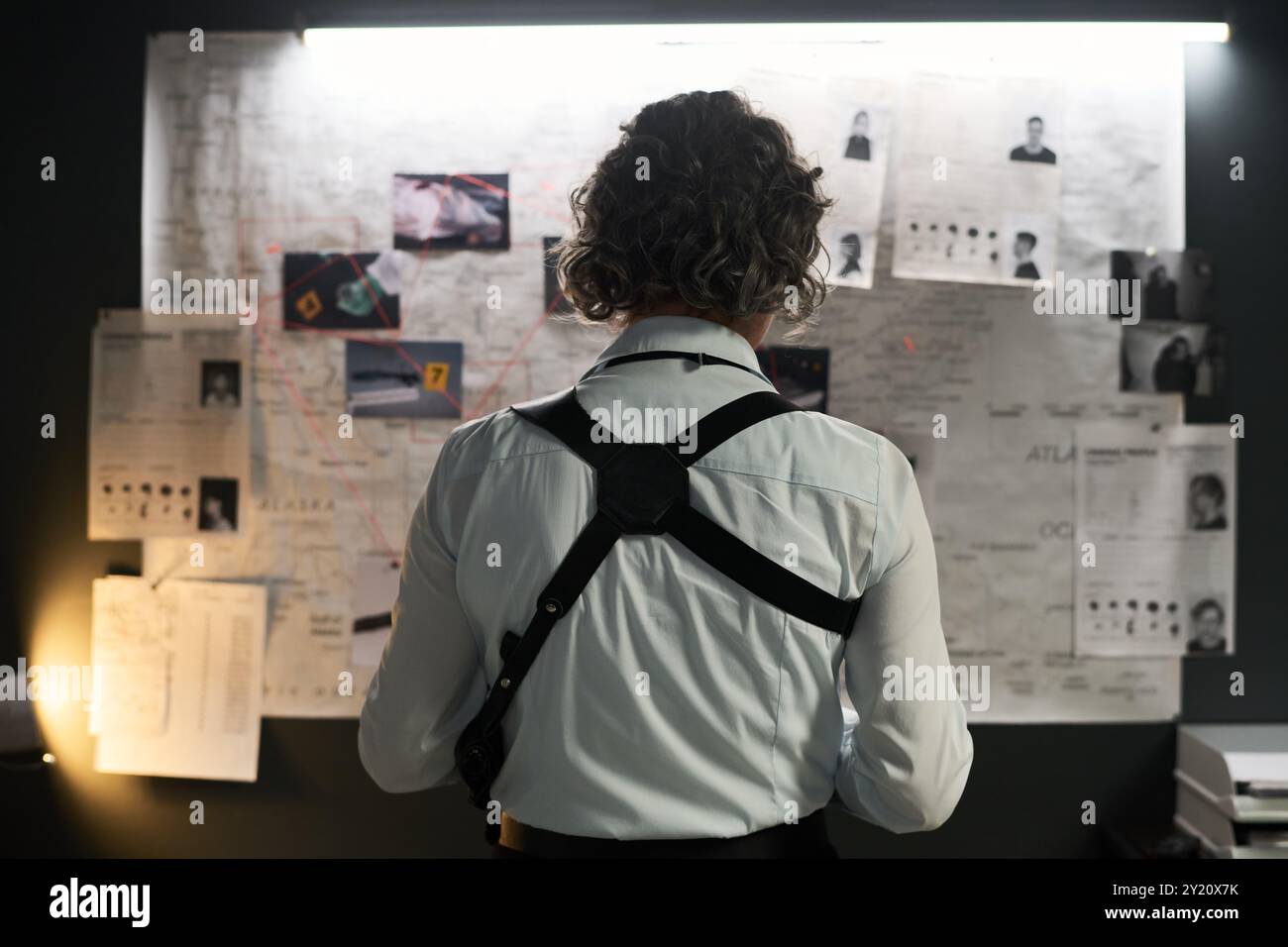 Person wearing white shirt and harness examining large map with crime ...