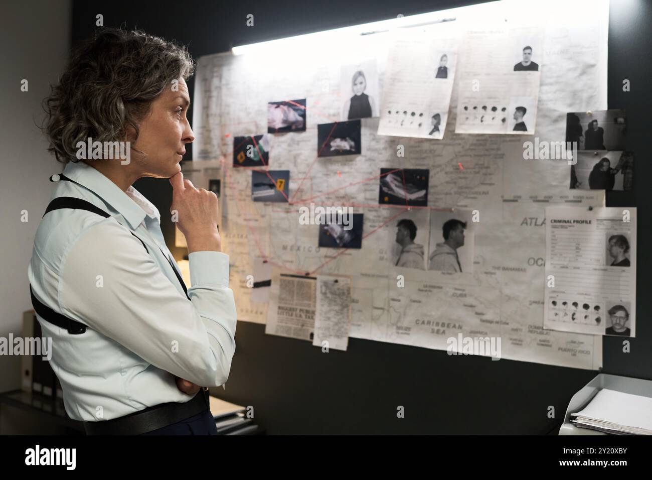 Detective studying crime evidence board with focused expression ...