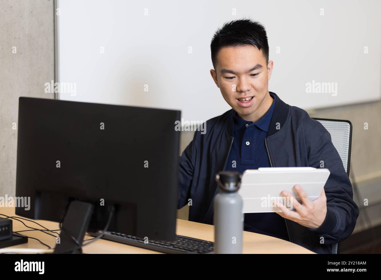 A young Asian college student is focused while studying at the computer ...