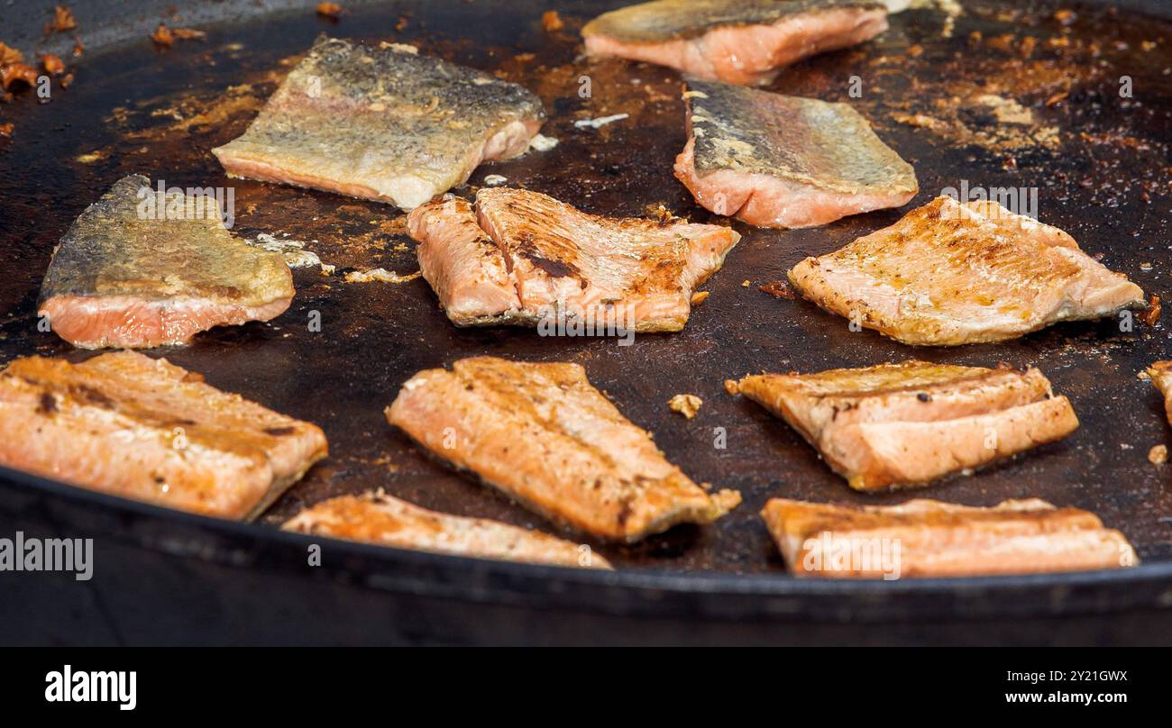 Grilled fish pieces on large metal pan with crispy skin, freshly cooked ...